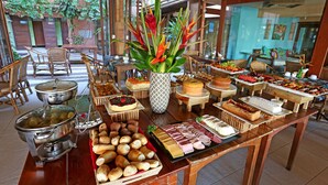Uma mesa de buffet com diversos alimentos e um vaso decorativo.