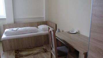 Quarto pequeno e funcional com cama, escrivaninha e cadeira.