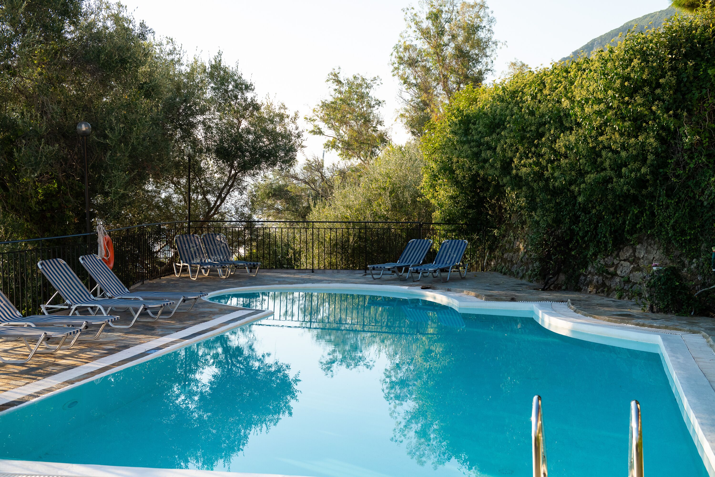 Uma piscina com espreguiçadeiras e uma parede de pedra.