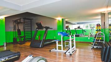 Uma academia com esteiras, simulador de escada e equipamentos de musculação.