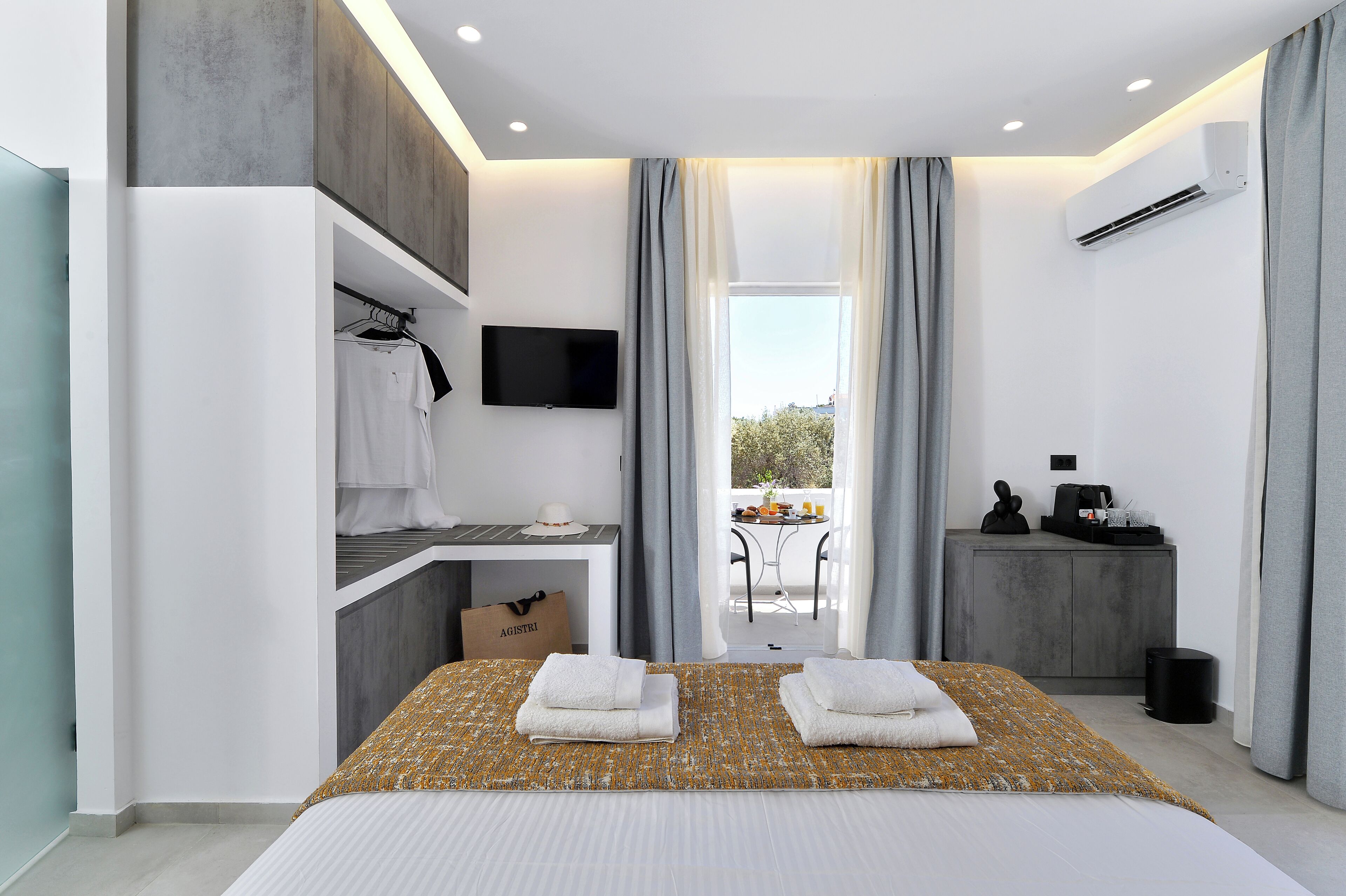 Quarto de hotel moderno com uma cama, uma mesa, uma TV e vista para o exterior.