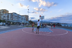 Quadra de basquete ao ar livre com paisagem urbana ao fundo.