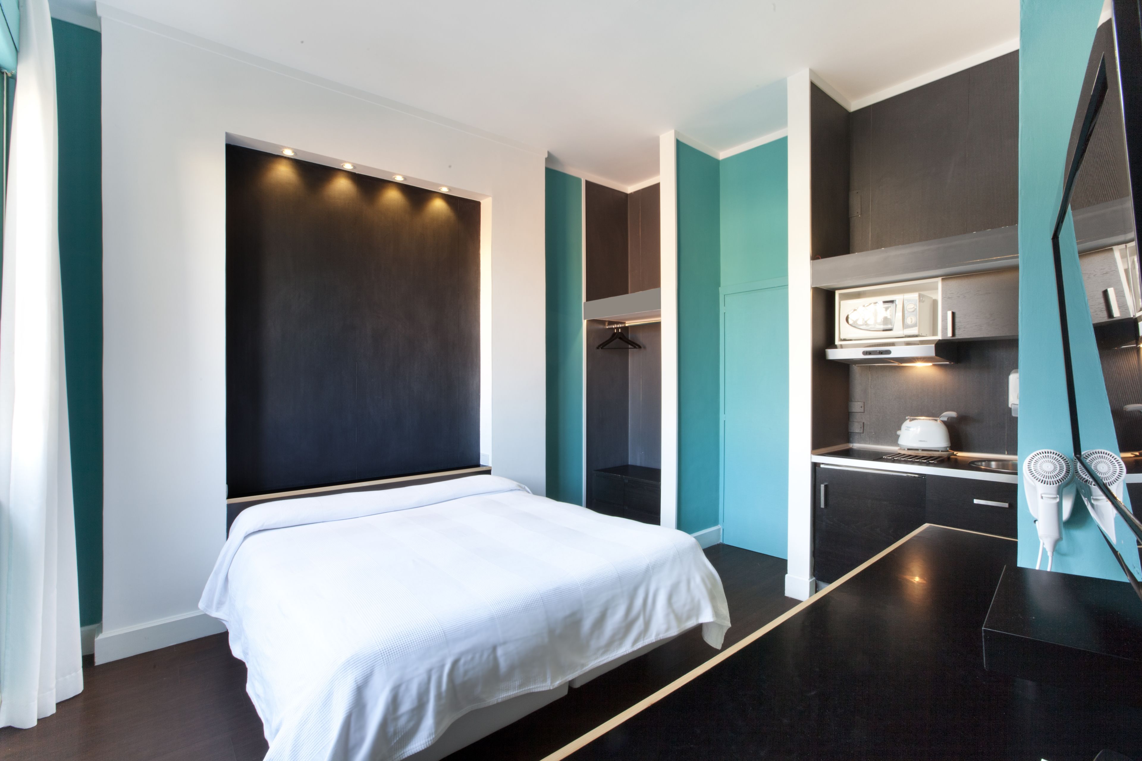 Quarto de hotel moderno com uma cama grande, uma cozinha compacta e um closet espaçoso.