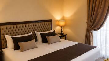 Quarto de hotel com uma cama grande, uma mesa de cabeceira, um abajur e vista para o exterior.