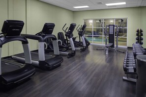 Uma academia com esteiras, elípticos e equipamentos de musculação.