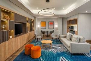 Uma sala de estar moderna com um sofá, duas poltronas, uma mesa de centro e um tapete estampado.