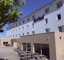 Hotel Kyriad com área de estar ao ar livre e estacionamento.