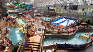 Um parque aquático interno com várias piscinas, toboáguas e uma grande área coberta.