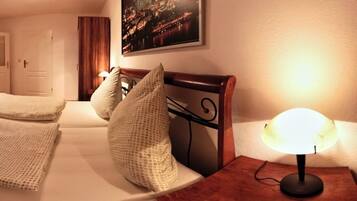Quarto de hotel com cama bem arrumada, mesa de cabeceira com abajur e pintura de paisagem urbana na parede.