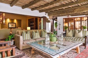 Uma sala de estar aconchegante com teto de madeira, mesa de centro de vidro e sofás listrados.