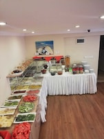 Mesa de buffet com diversos alimentos e utensílios.