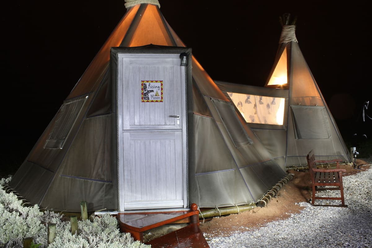 Uma tenda grande e cónica com uma porta identificada como "Rising Moon".