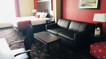 Quarto de hotel com cama, sofá de couro, mesa pequena, cadeira e escrivaninha.