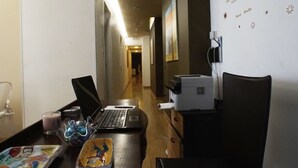 Quarto de hotel com escrivaninha, laptop, impressora e objetos decorativos.