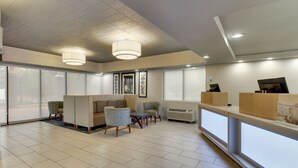 Um saguão de hotel moderno com balcão de recepção, área de estar e grandes janelas.