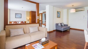 Uma sala de estar com um sofá bege, um sofá cinza, piso de madeira e um espelho grande.