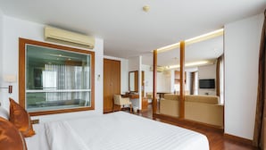 Quarto de hotel com uma cama grande, uma escrivaninha, um sofá e uma televisão.