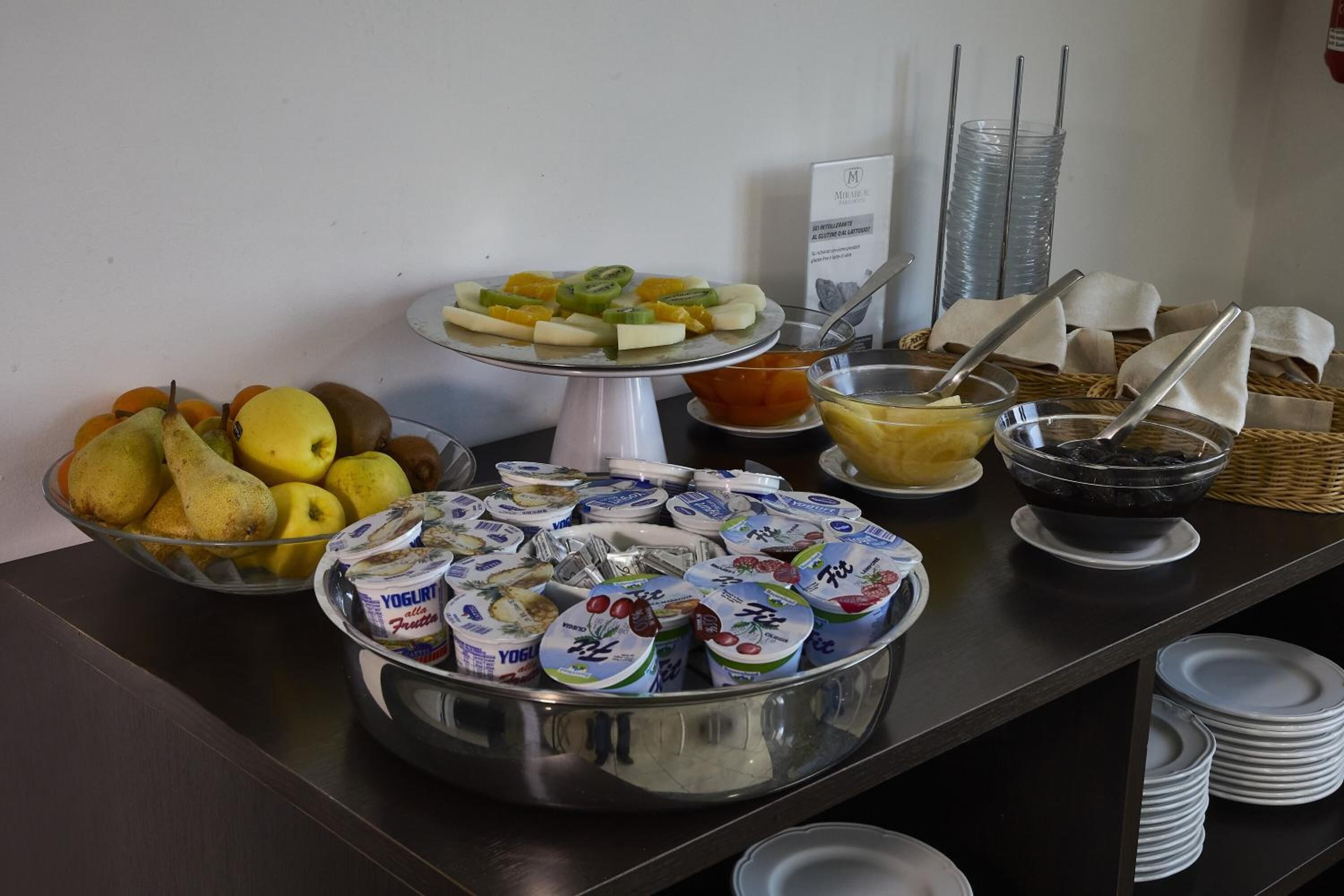 Buffet com frutas, iogurte e outros alimentos.