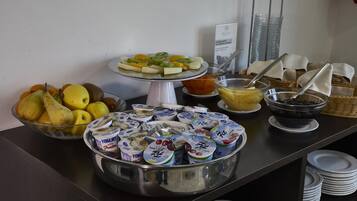 Buffet com frutas, iogurte e outros alimentos.