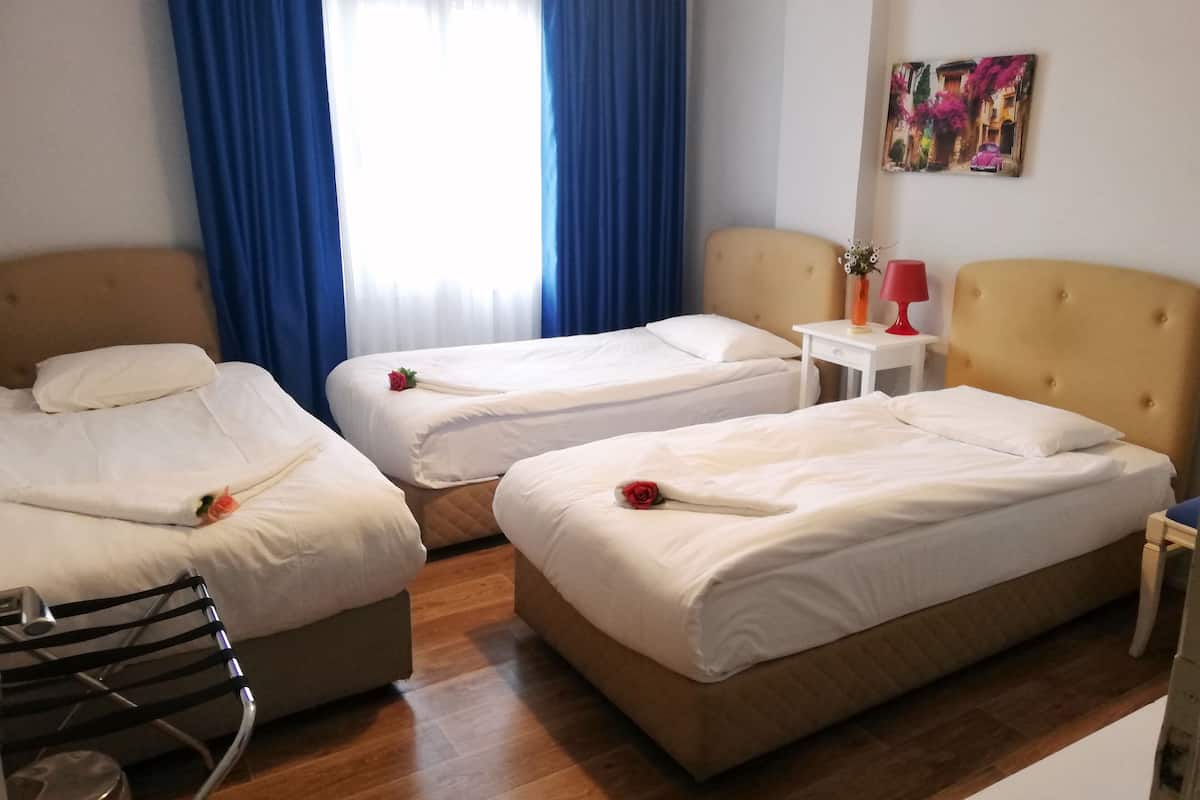 Quarto de hotel com duas camas, uma mesinha, uma cadeira e um quadro na parede.
