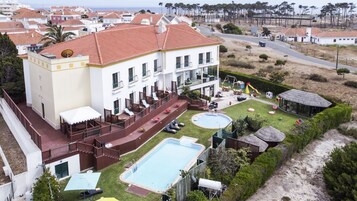 Um edifício grande com piscina, área de estar externa e jardim cercado.