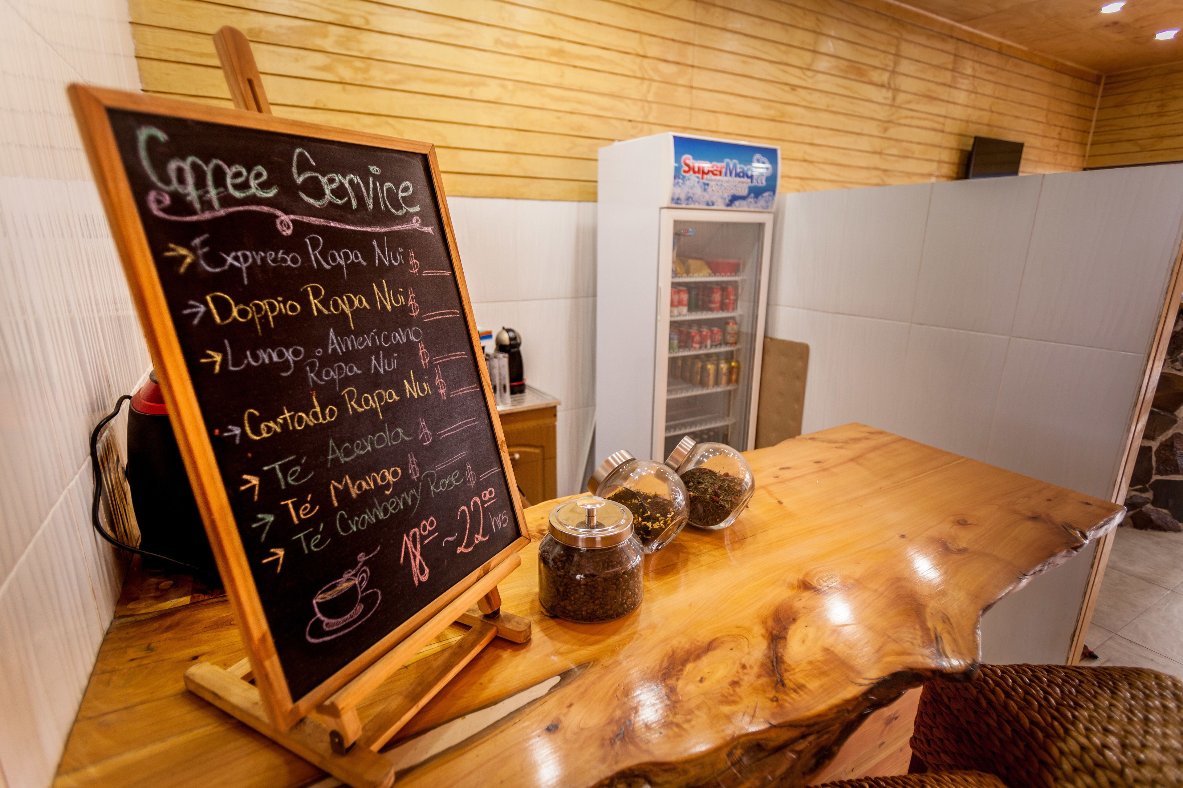 Uma cafeteria com cardápio na lousa listando expresso, cappuccino e latte. Há potes de grãos de café no balcão.