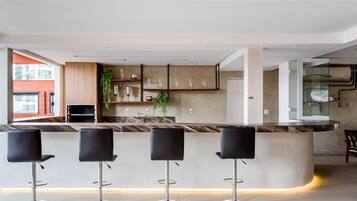 Cozinha moderna com bancada de mármore, três banquetas pretas e uma janela grande.