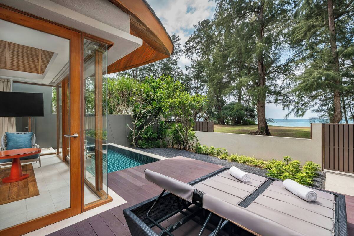 Uma área de estar ao ar livre moderna com piscina, deck de madeira e vista para o mar.