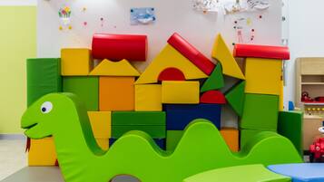 Uma área de recreação infantil com blocos de construção coloridos e um brinquedo de dinossauro verde.