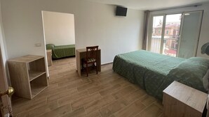 Quarto compacto com cama, escrivaninha e cadeira.