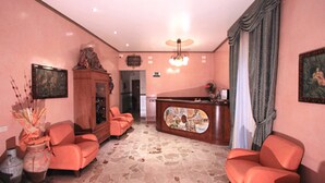 Um quarto com piso de pedra, um balcão de recepção e duas poltronas laranjas.