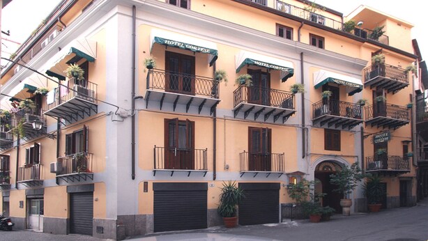 Um edifício com várias andares, varandas, garagem e plantas em vasos.