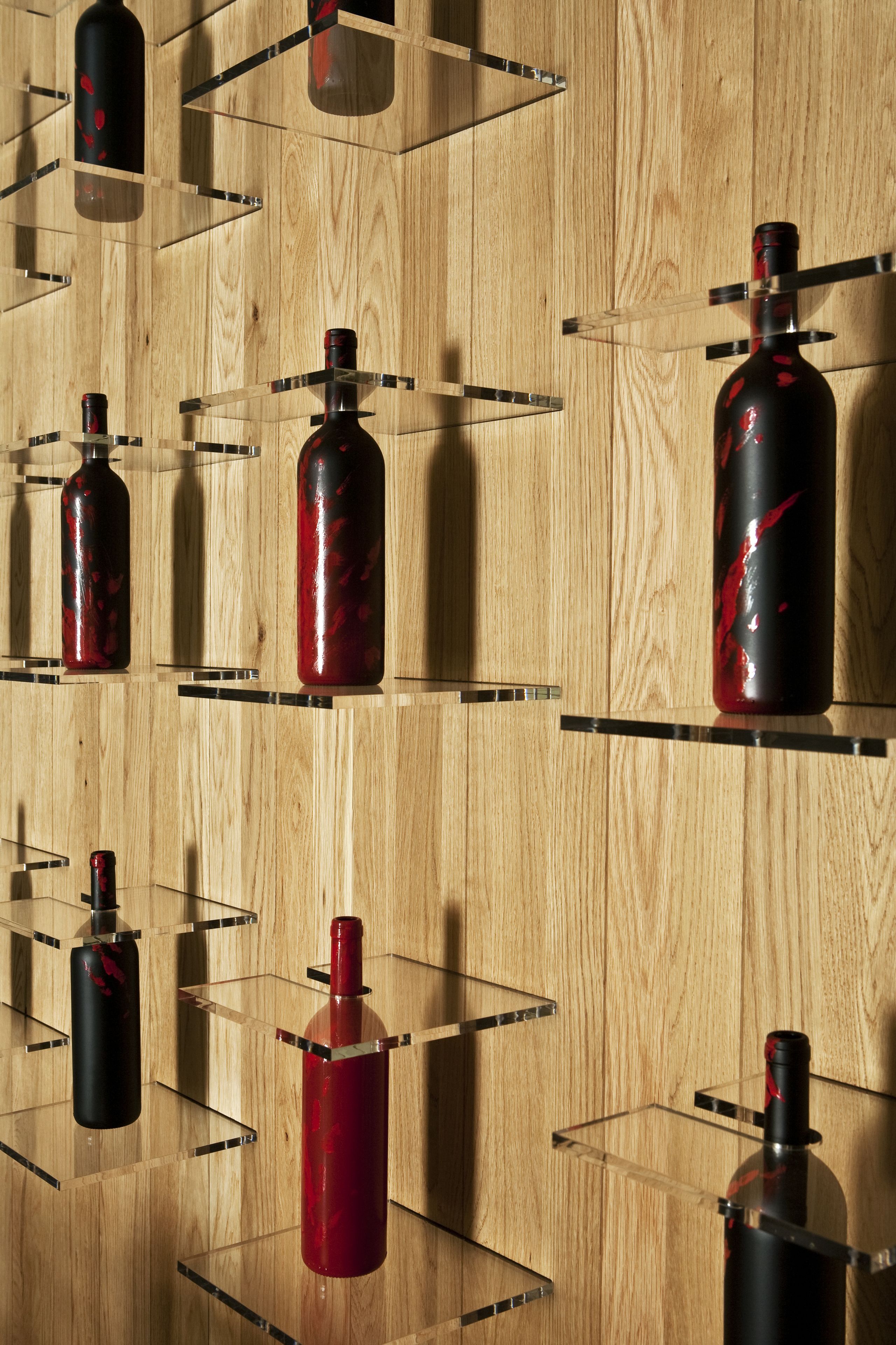 Pared de madeira com várias prateleiras de vidro transparente para garrafas de vinho.