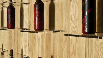 Pared de madeira com várias prateleiras de vidro transparente para garrafas de vinho.