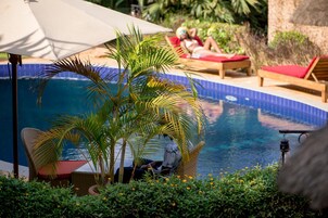 Piscina com espreguiçadeiras e uma palmeira.