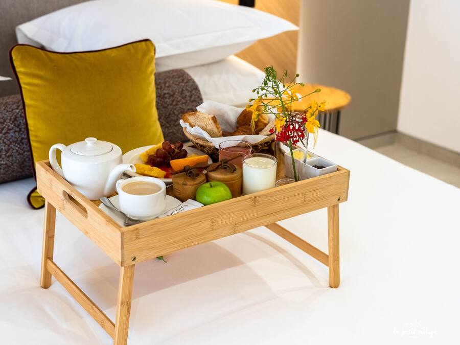 Bandeja de café da manhã em uma cama com travesseiro branco, travesseiro amarelo e cabeceira de madeira.