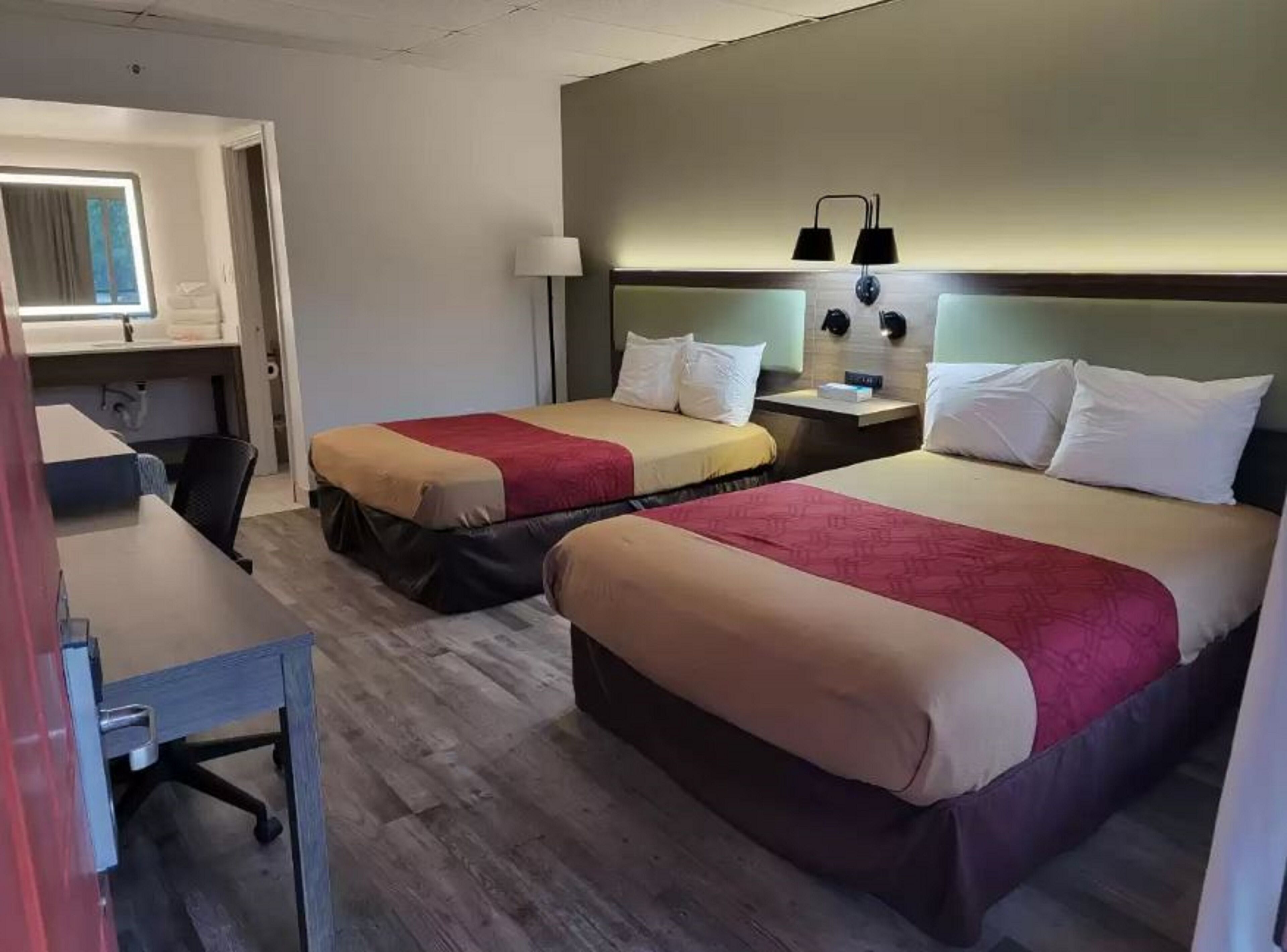 Quarto de hotel com duas camas, uma escrivaninha e uma cadeira.