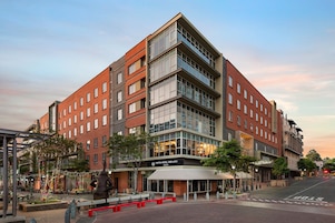 Um hotel com vários andares e design moderno, com janelas amplas e uma entrada imponente.