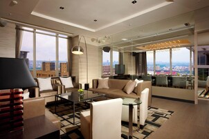 Uma sala de estar moderna com sofá, mesa de centro e vista da cidade através de grandes janelas.