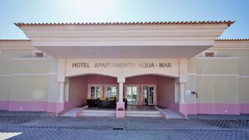 Entrada de hotel com uma placa que diz 'HOTEL APARTAMENTO AQUA-MAR'.