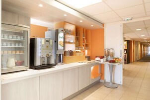 Cozinha moderna com geladeira, cafeteira e balcão com diversos alimentos e utensílios de cozinha.