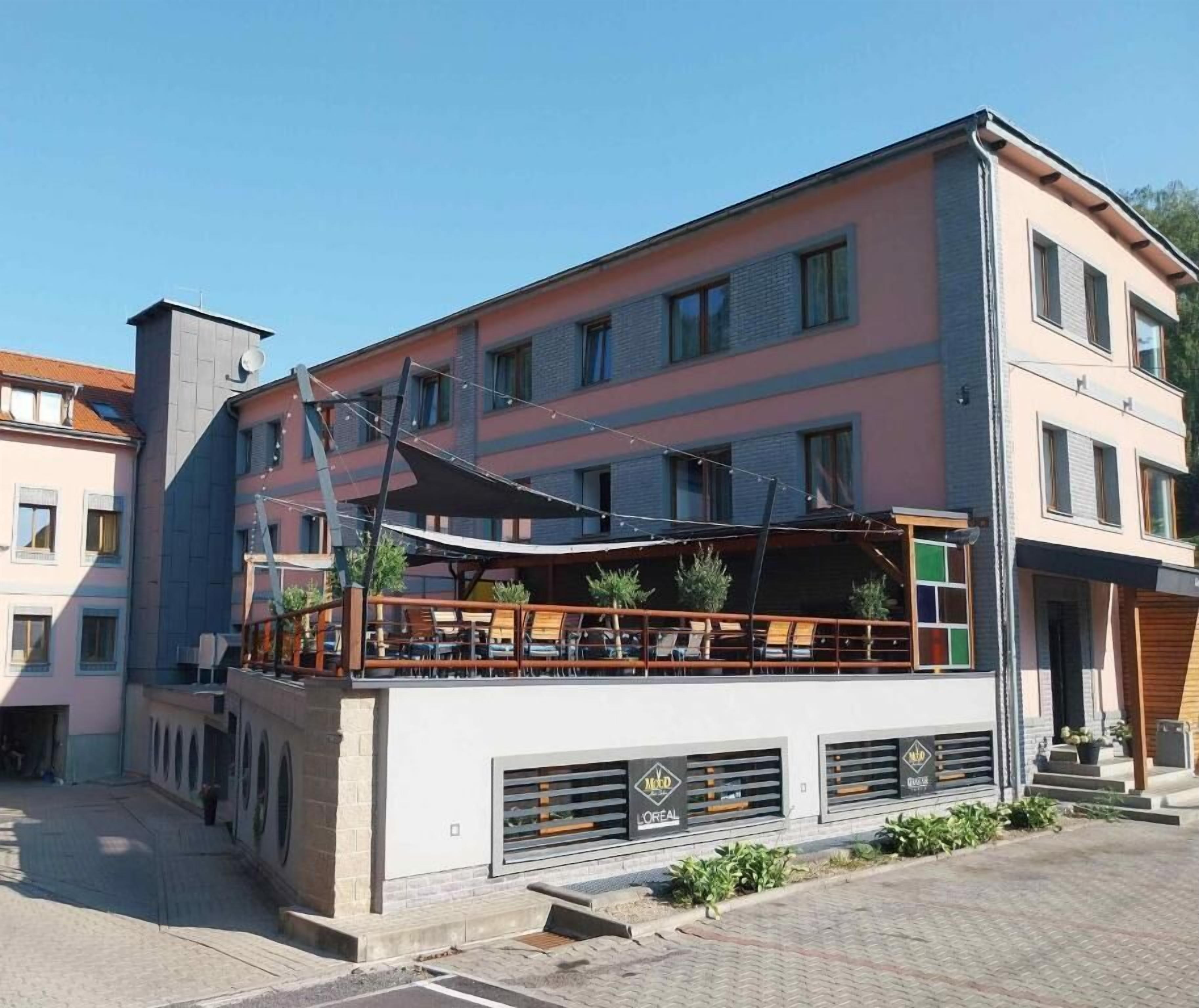 Um hotel com vários andares, área externa coberta para sentar e fachada moderna.