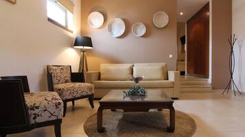 Uma sala de estar com um sofá, duas poltronas, uma mesa de centro e cestos decorativos na parede.