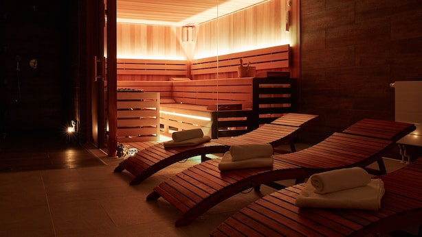 Uma sala de sauna com bancos de madeira, incluindo bancos com toalhas.