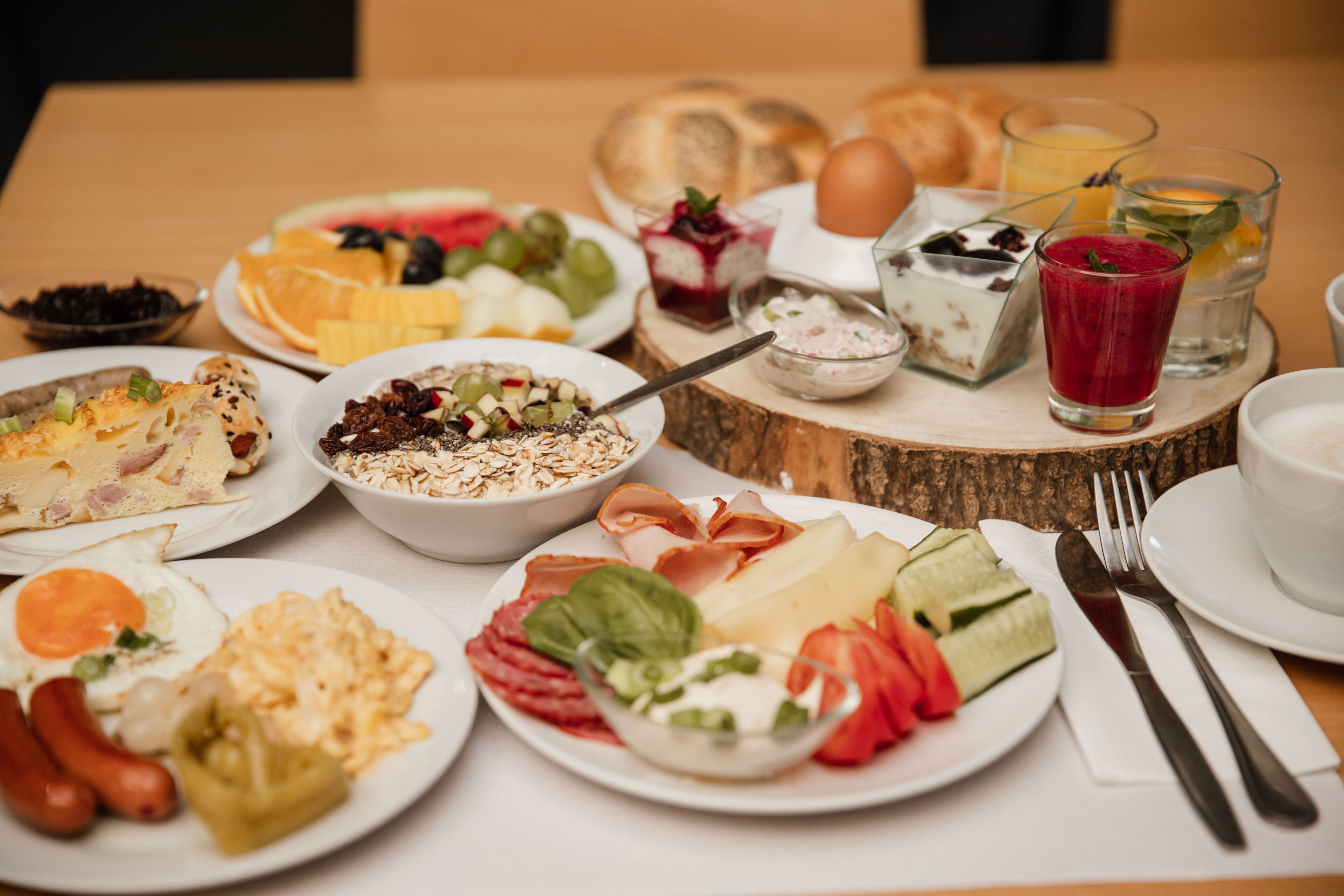 Um buffet de café da manhã com diversos pratos, incluindo ovos, linguiça, queijo e frutas.