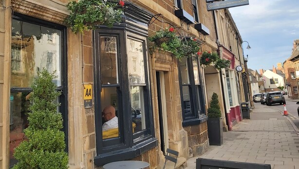 Um pub tradicional com uma placa que diz "The Crown Uppingham" e uma placa indicando "16m Coaching Inn with Rooms".