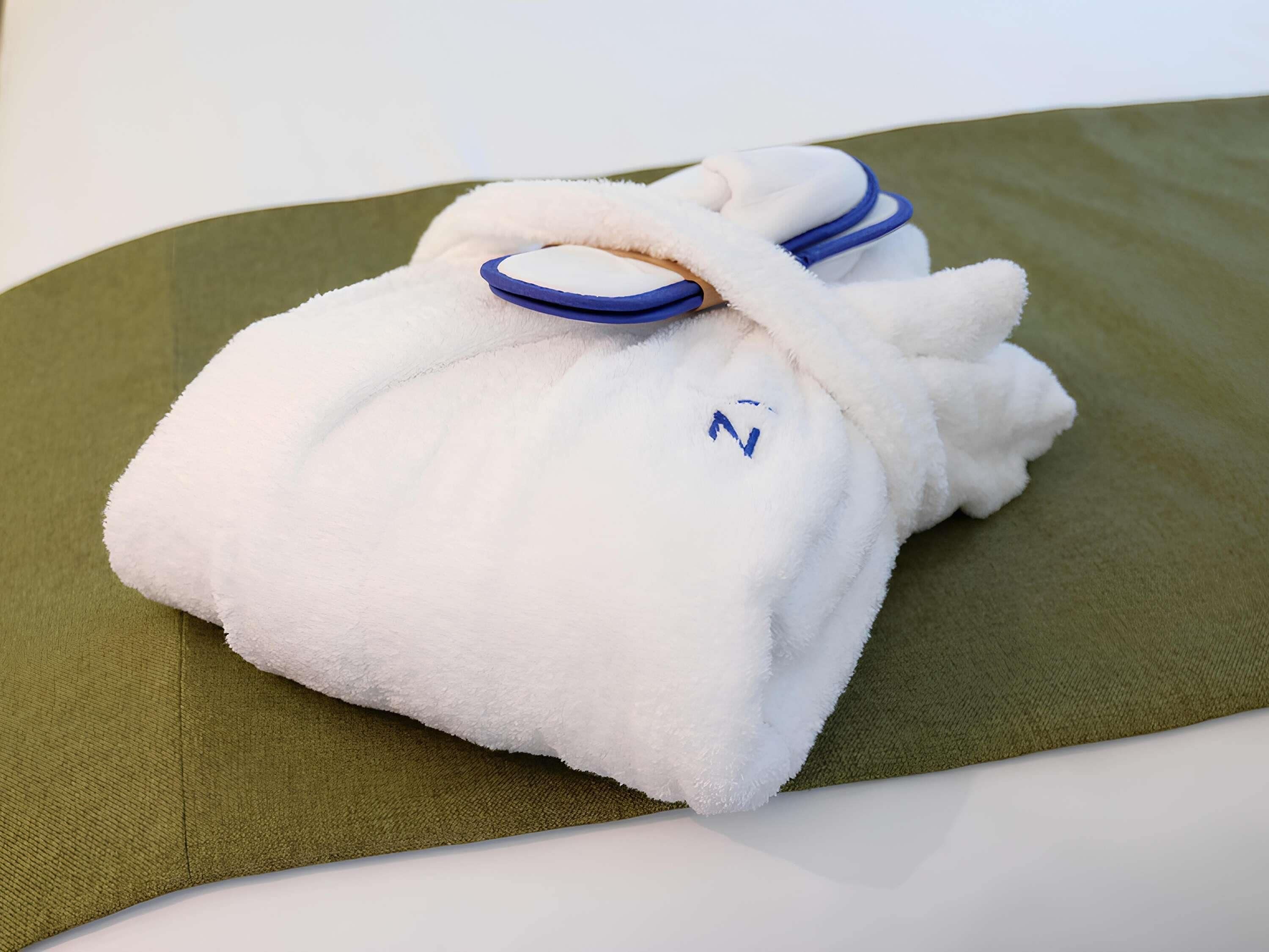 Uma sacola branca e fofa, com alça azul e um pequeno logo azul sobre uma superfície verde.