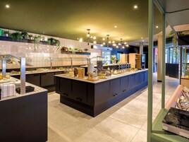 Uma cozinha moderna com uma ilha central, diversos alimentos e uma vitrine de vidro.