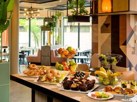 Uma mesa de buffet com diversos itens de comida, incluindo doces, frutas e sobremesas.
