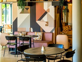 Um interior moderno com mesas e cadeiras redondas, um sofá com almofadas estampadas e um design geométrico na parede.